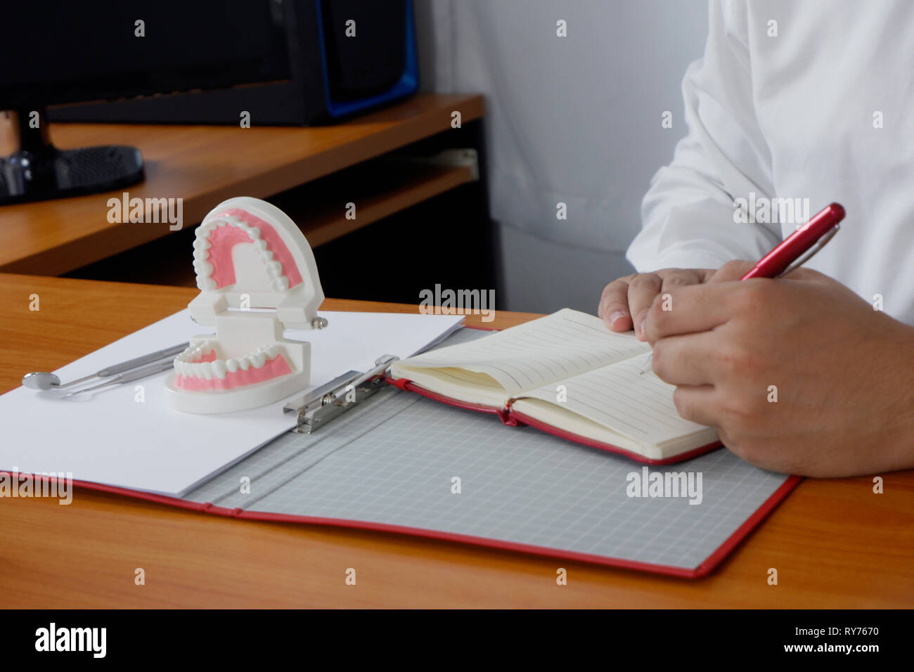 dentist sitting at table with tooth model and tools in professional ...