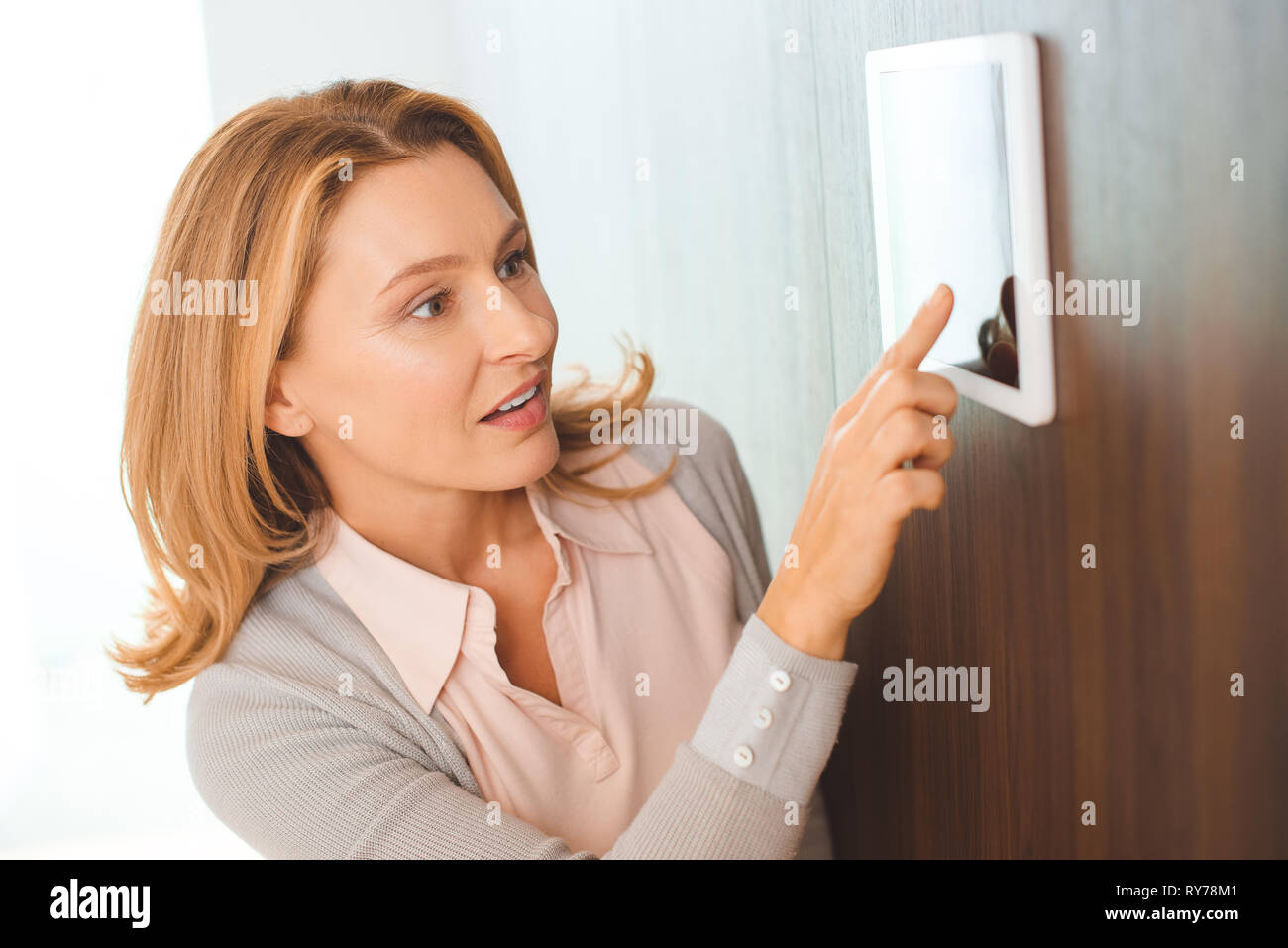 pretty blonde woman using smart home control panel Stock Photo - Alamy