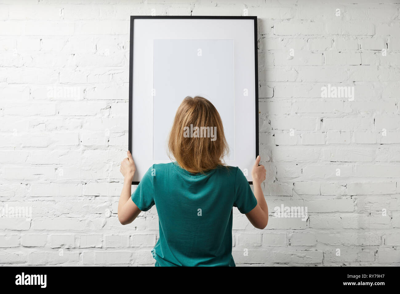back view of woman holding mock up poster in frame Stock Photo - Alamy