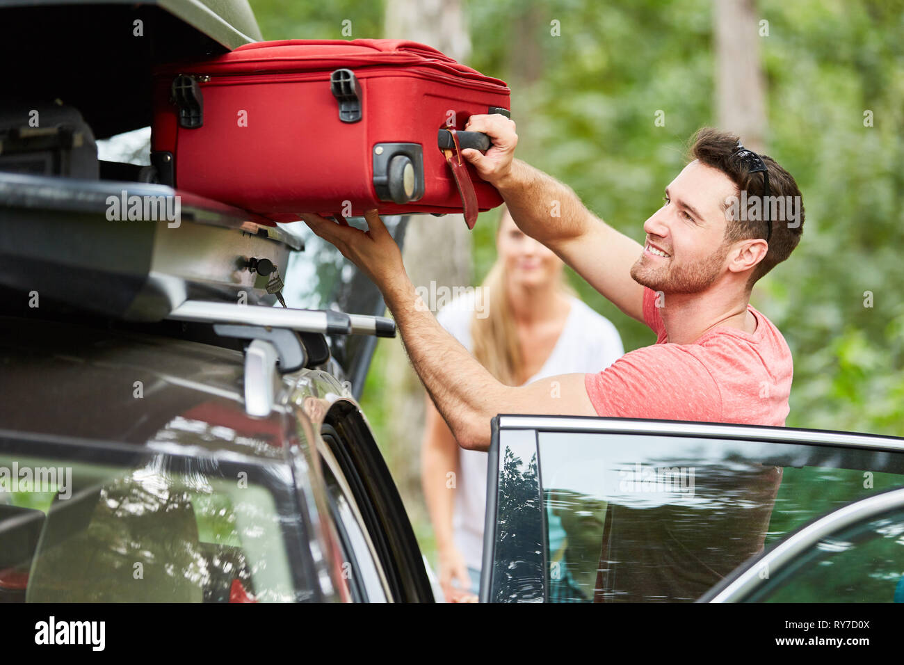 Man packs suitcases in the roof box on the car before traveling on ...