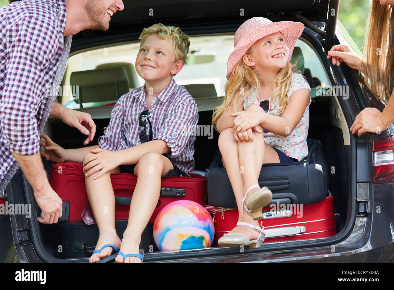 Family and children with luggage in the car in the trunk before ...