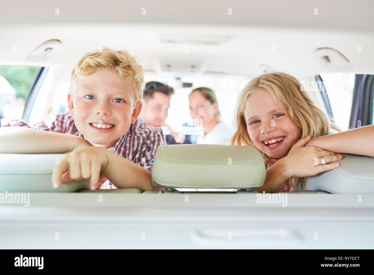 Two laughing kids in the back seat in the car with parents on family ...