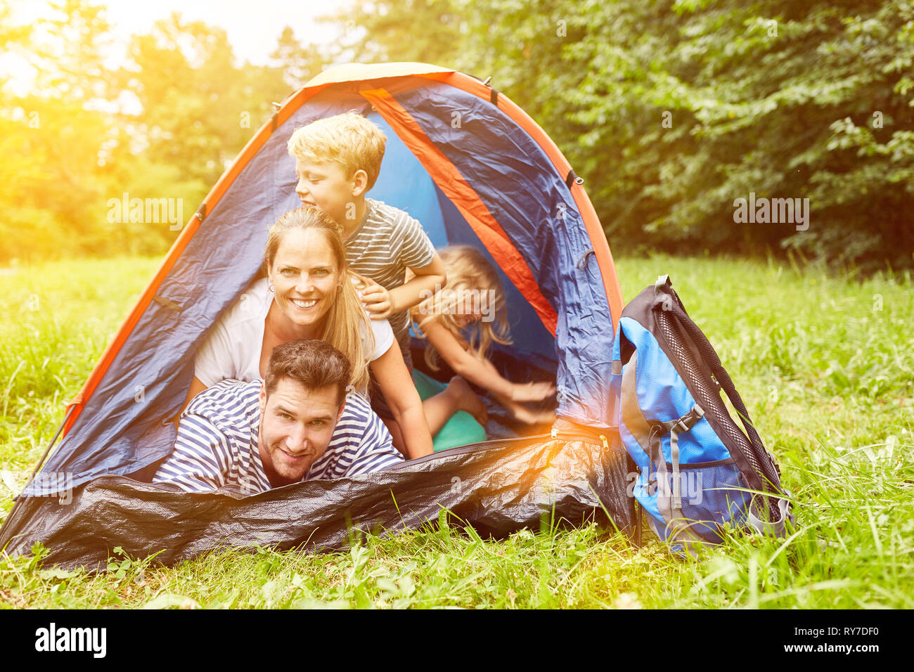 Happy family with children in tent while camping on campsite in summer ...