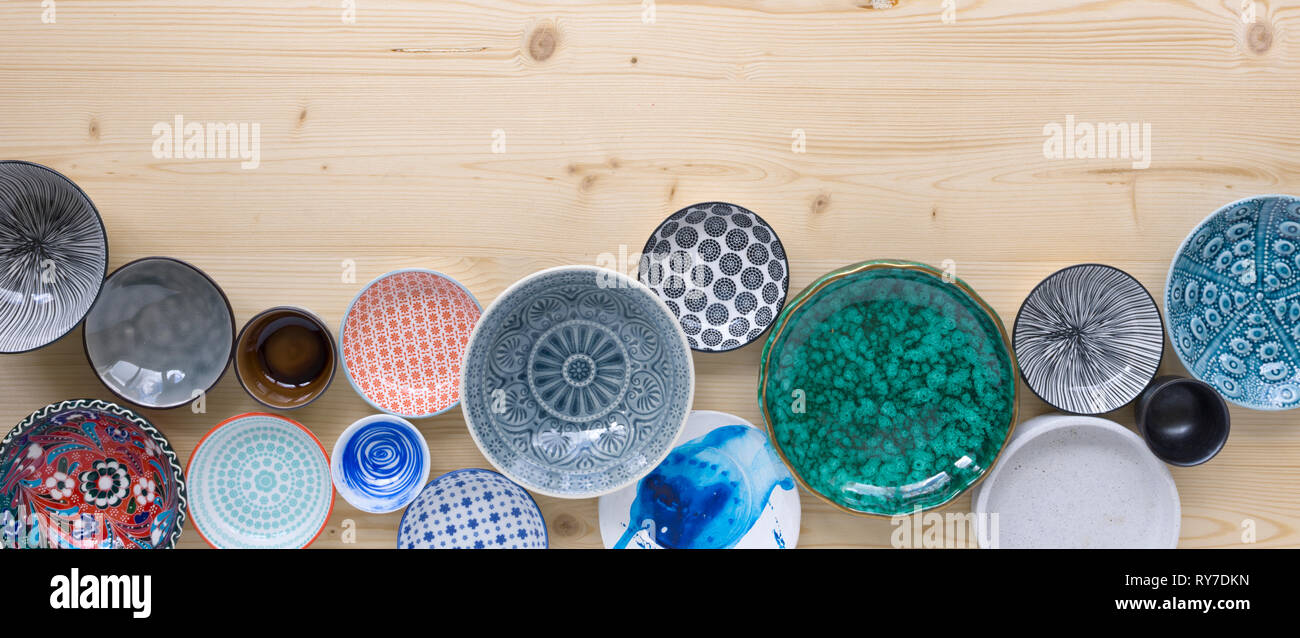 different kinds of modern colourful crockery on light wood background ...