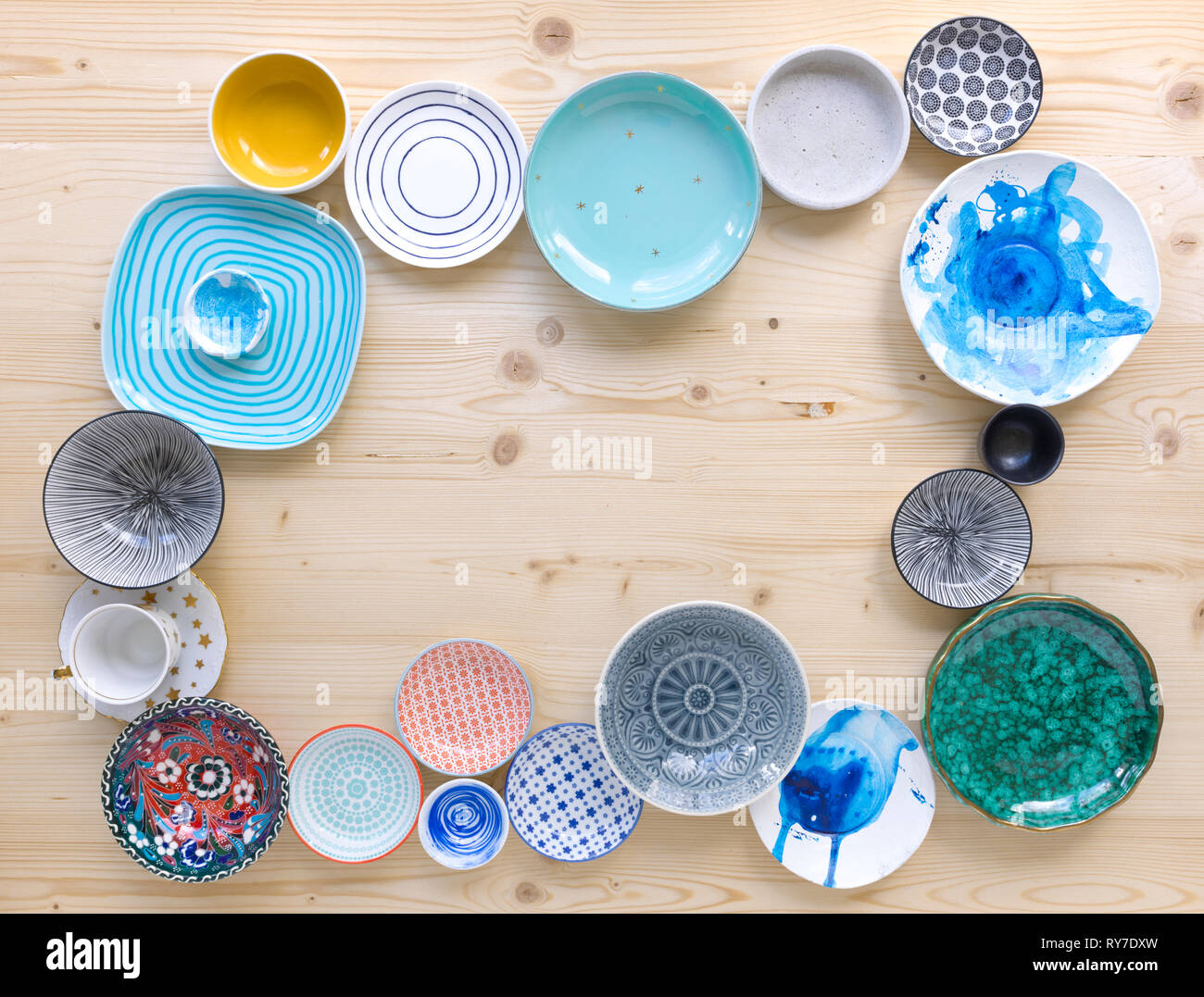different kinds of modern colourful crockery on light wood background ...