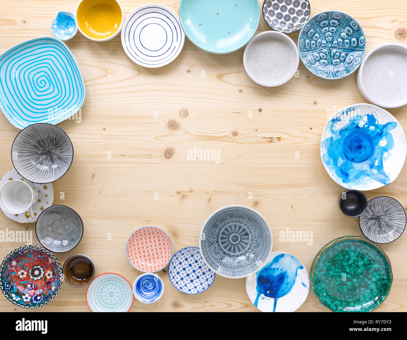 different kinds of modern colourful crockery on light wood background ...