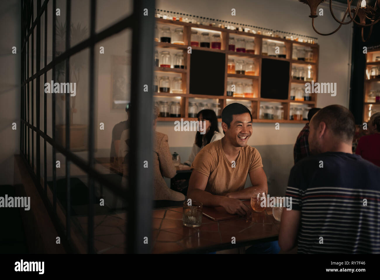 Friends laughing over drinking in a bar together at night Stock Photo ...