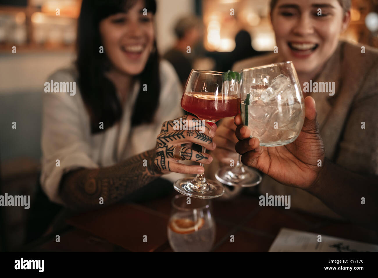 Smiling friends toasting together with drinks in a bar Stock Photo - Alamy