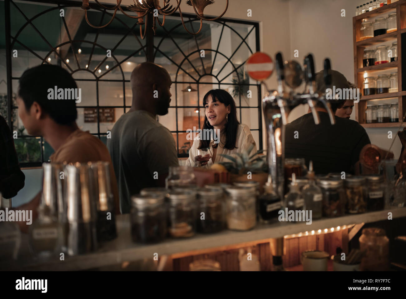 Diverse friends talking over drinks in a bar at night Stock Photo - Alamy