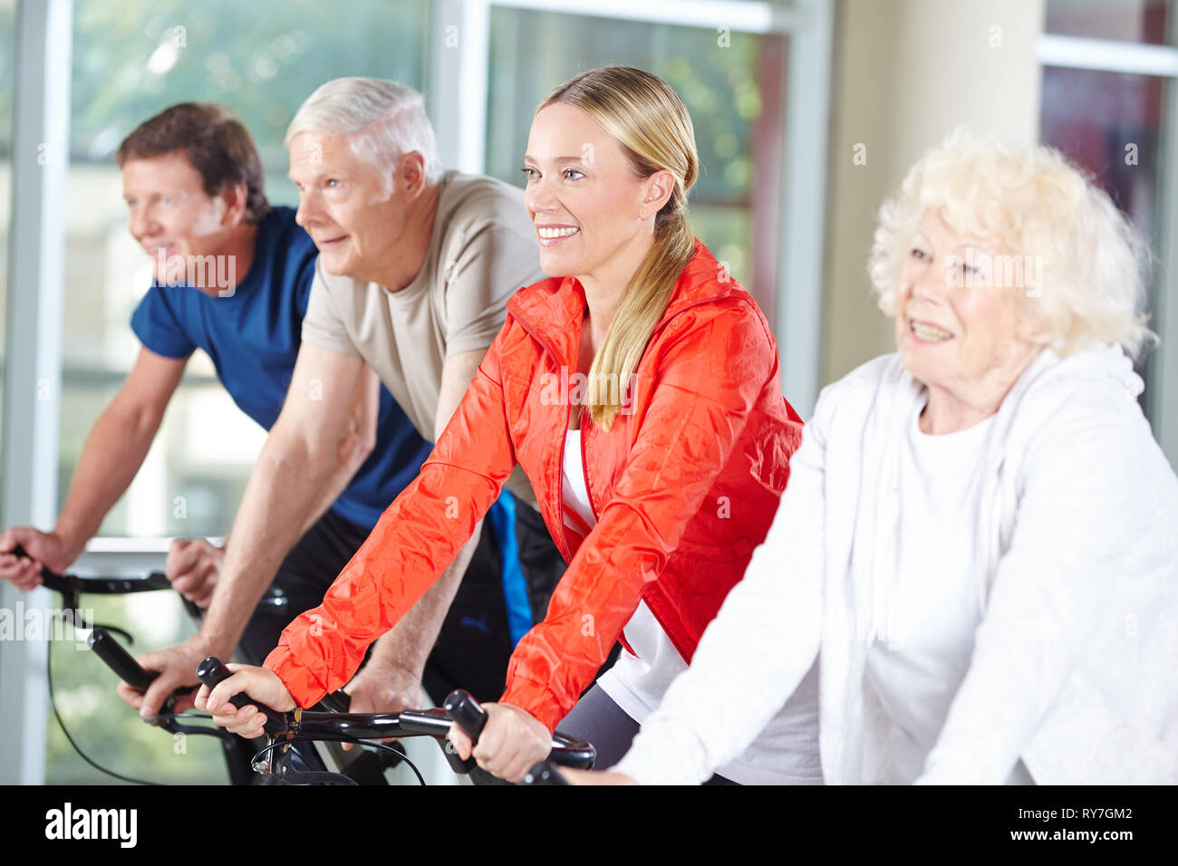 A happy group of seniors working together on spinning in the fitness ...