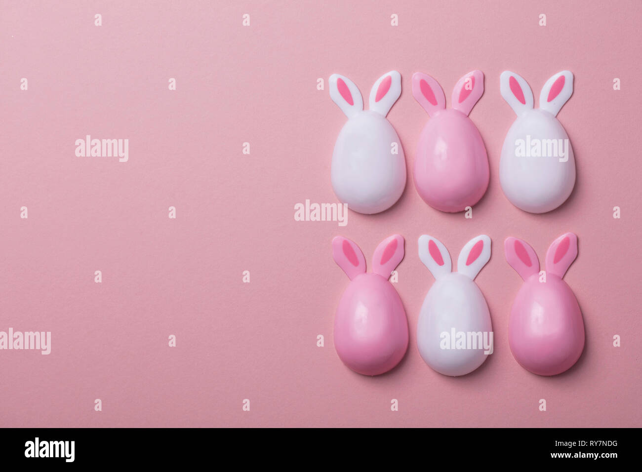 Easter eggs with bunny ears on a pastel pink background Stock Photo - Alamy