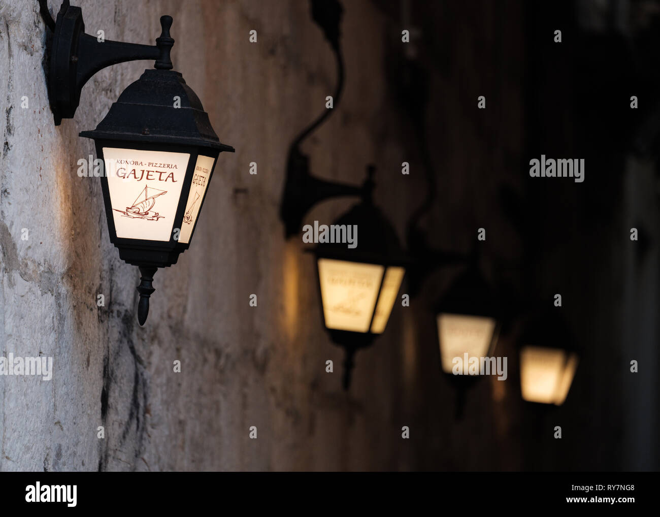 Four lit vintage street lamps advertising a local pizzeria, Dubrovnik ...