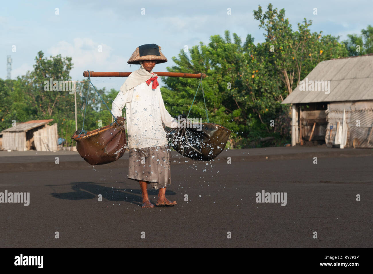 Bali Indonesia Apr 3, 2016 : Traditional salt farmer pouring sea water ...