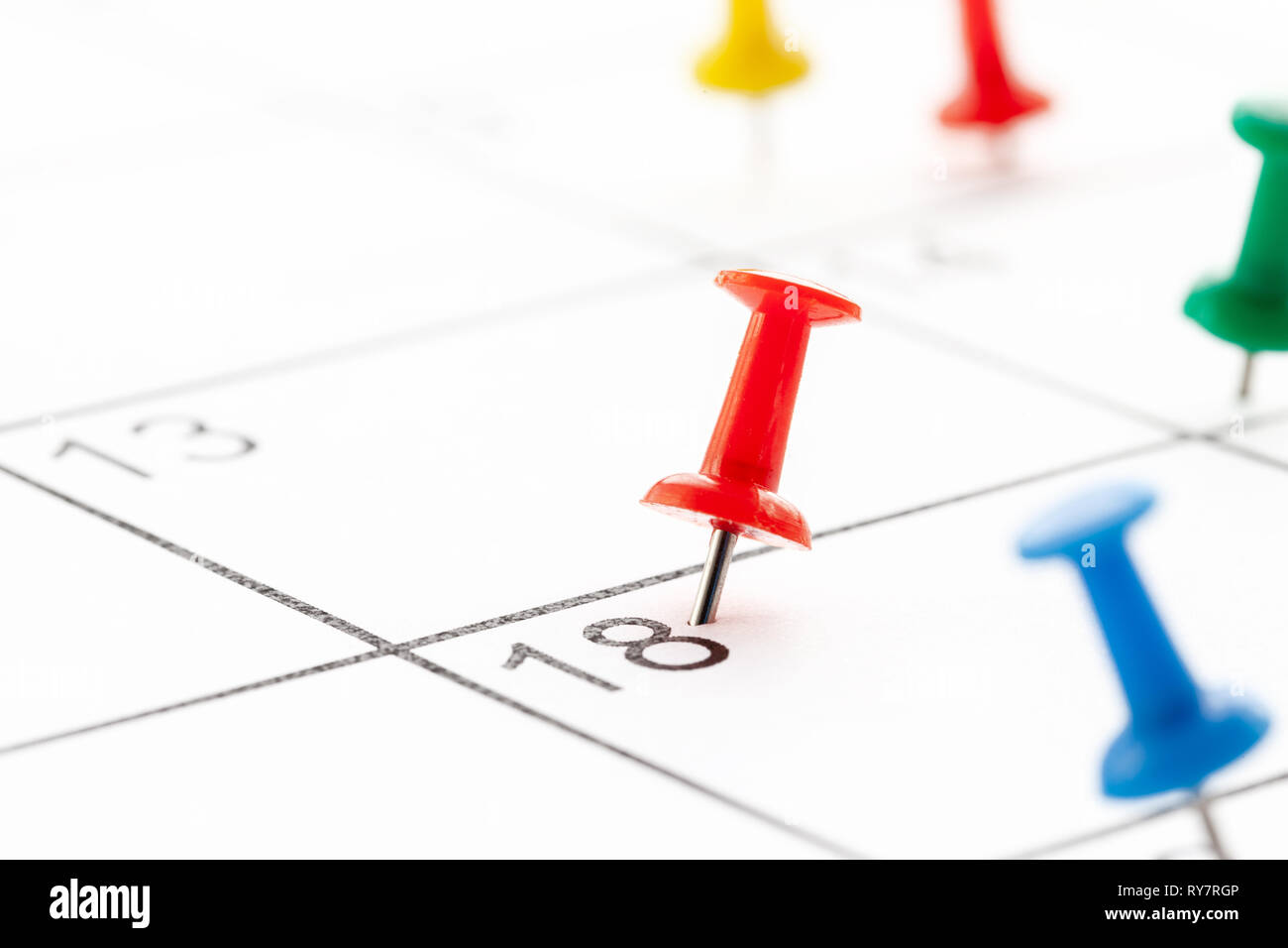 Colored push pin on white calendar background. Copy space for text ...