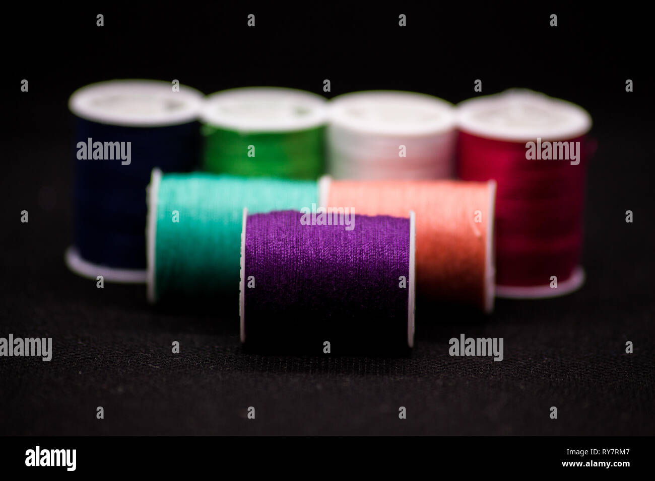 Colourful thread spools on a black background Stock Photo - Alamy