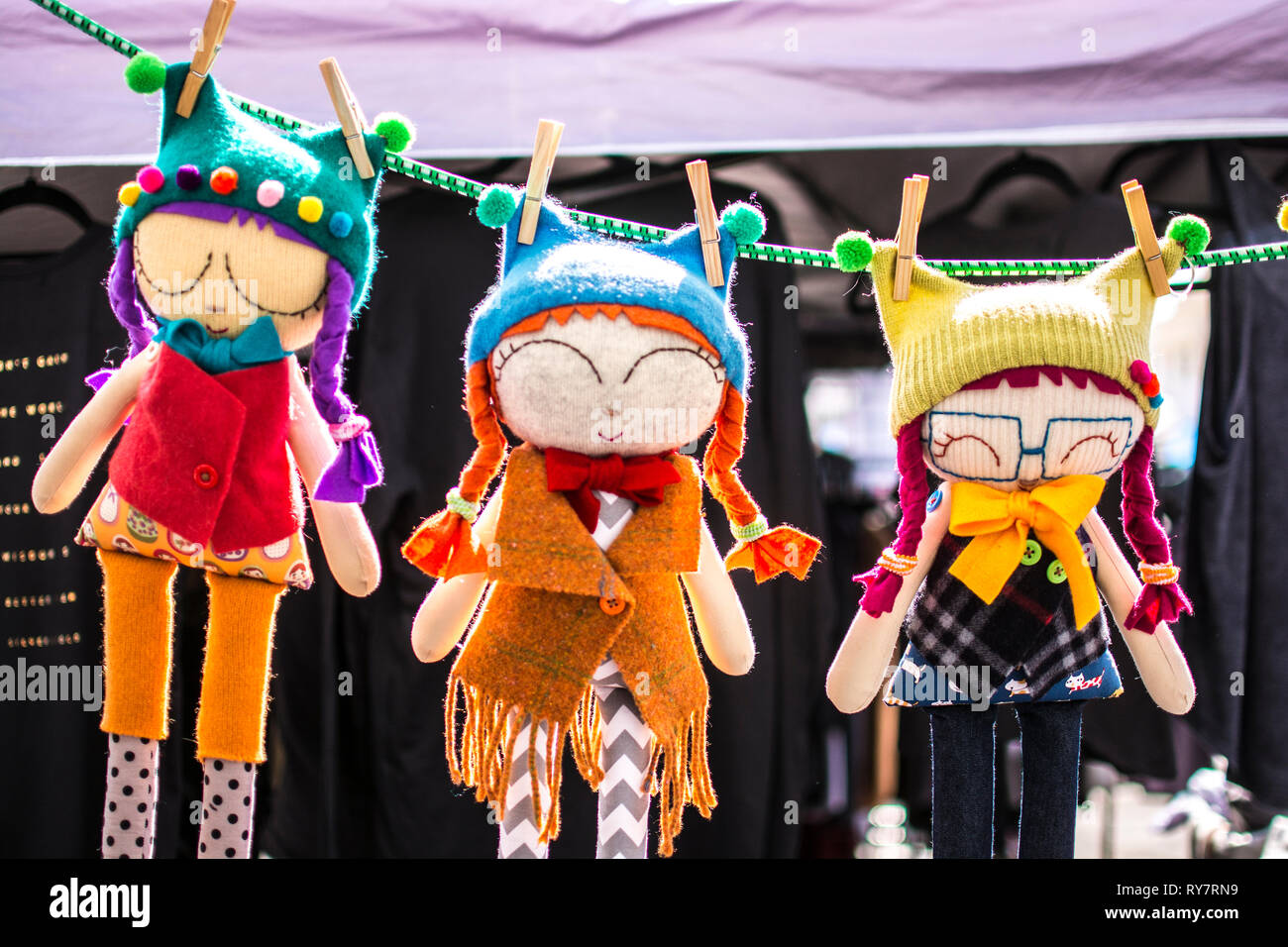 Three dolls, apparently made of cloth and yarn, hanging from a clothes ...