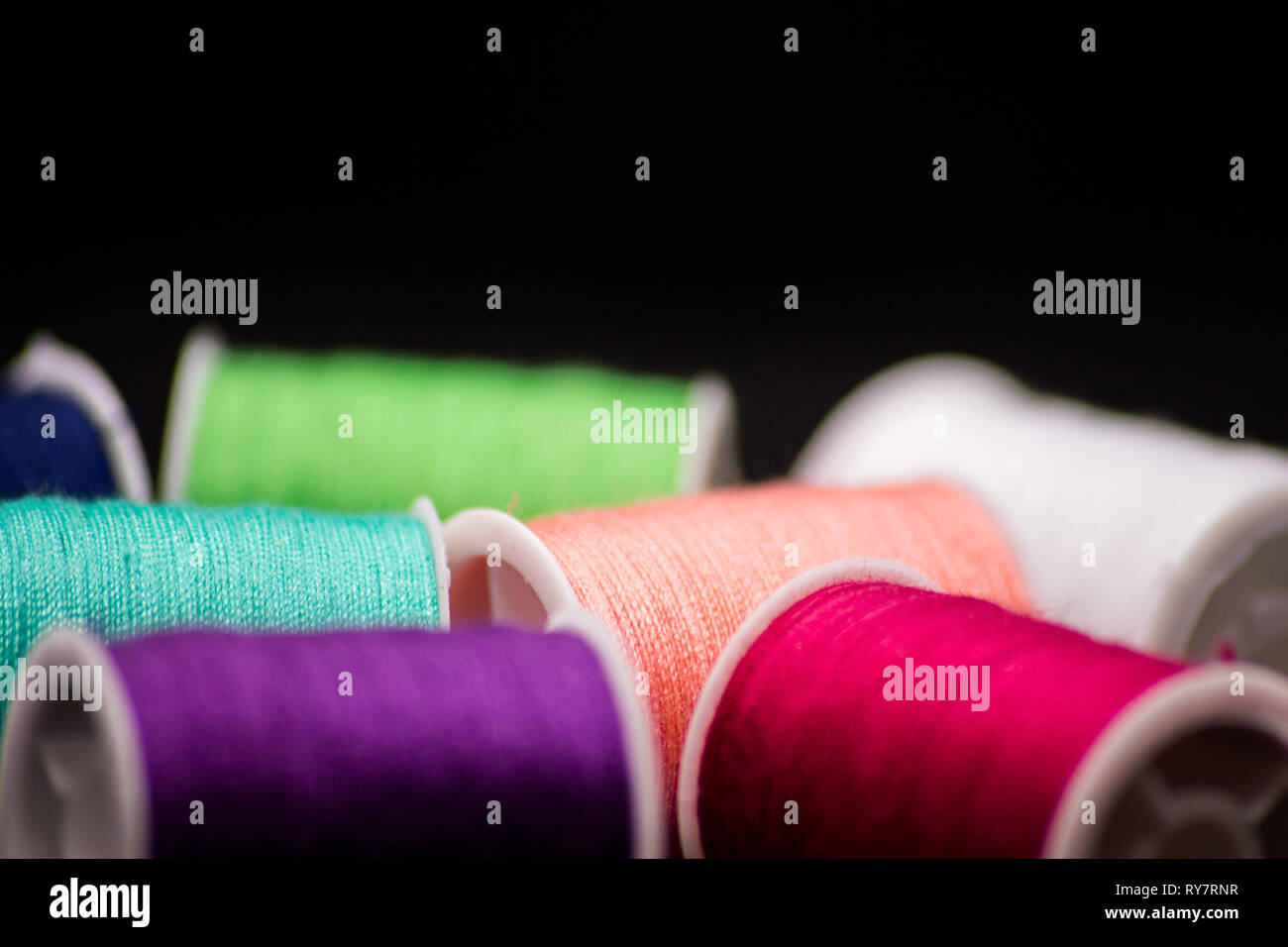 Colourful thread spools on a black background Stock Photo - Alamy