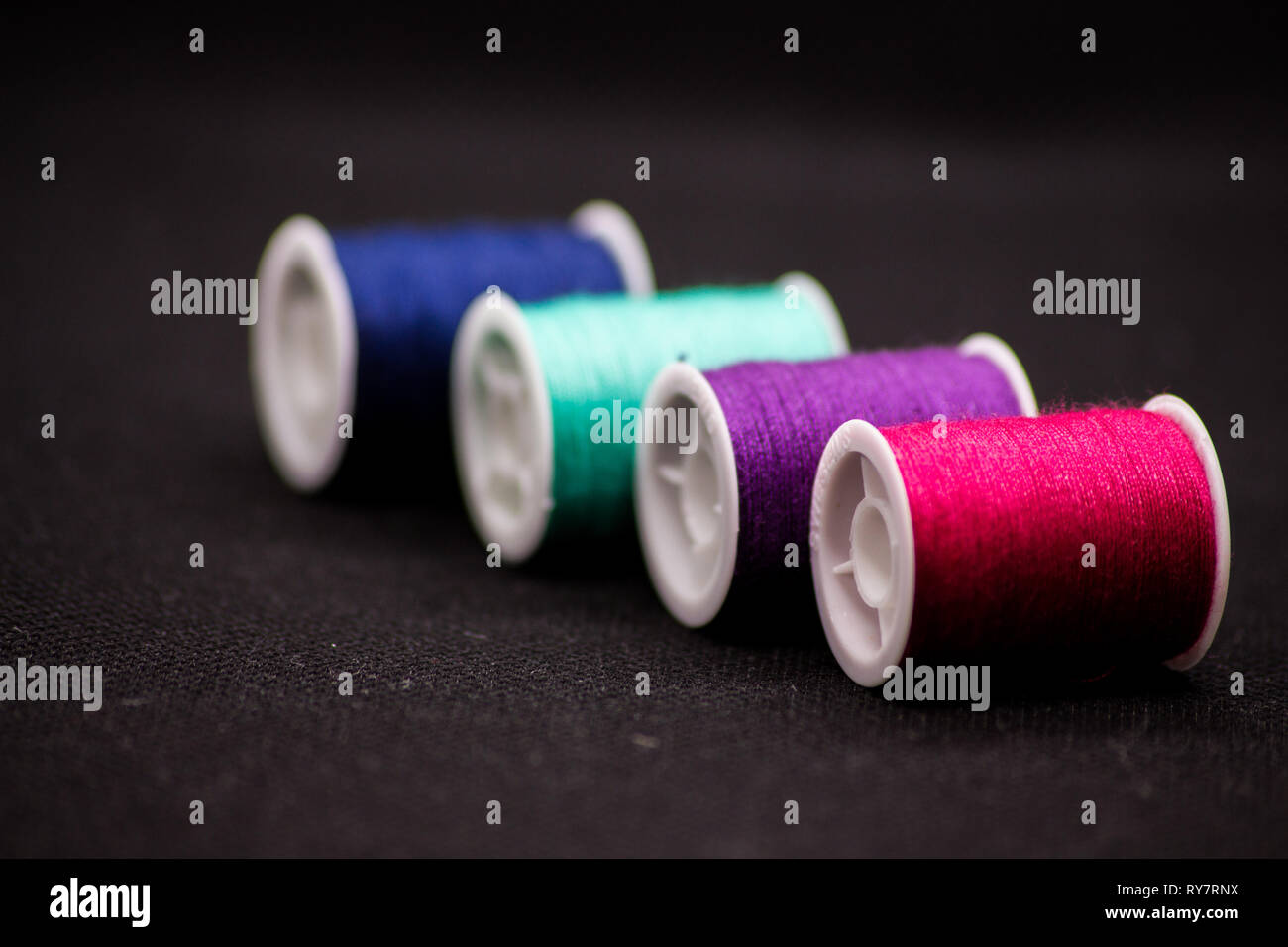 Colourful thread spools on a black background Stock Photo - Alamy