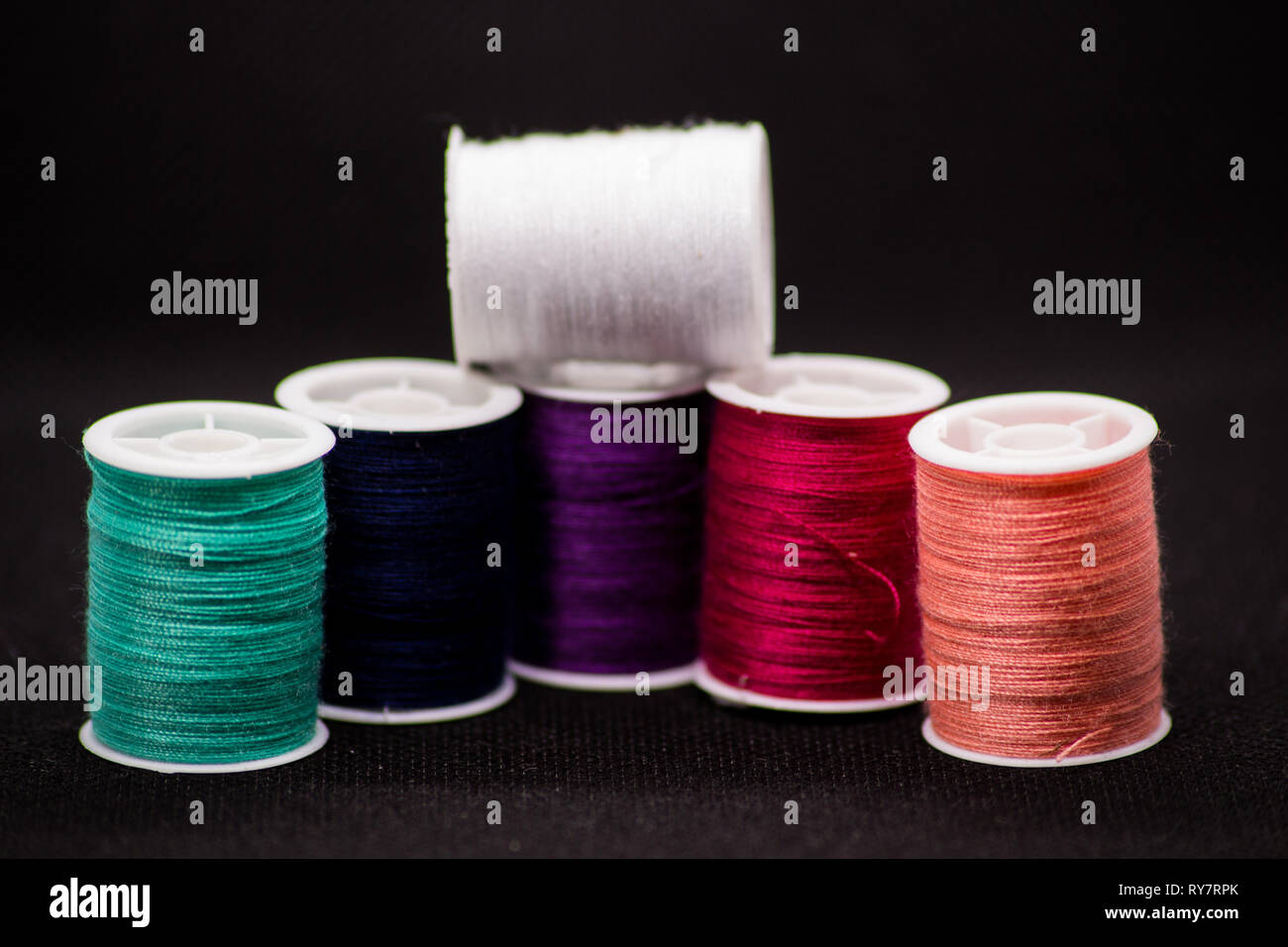 Colourful thread spools on a black background Stock Photo - Alamy