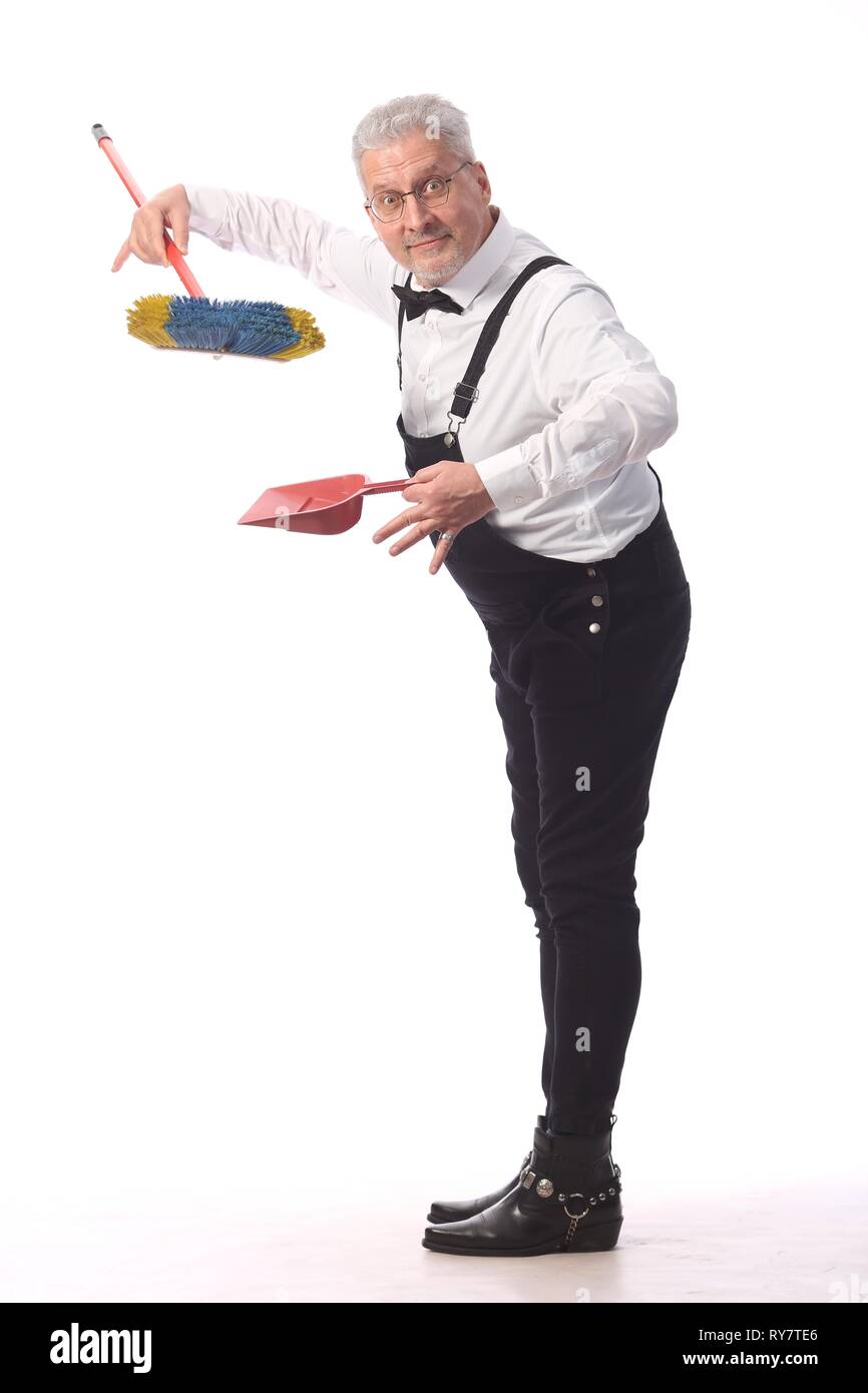 Gray-haired cleaner, janitor in a black jumpsuit with a mop and dustpan ...