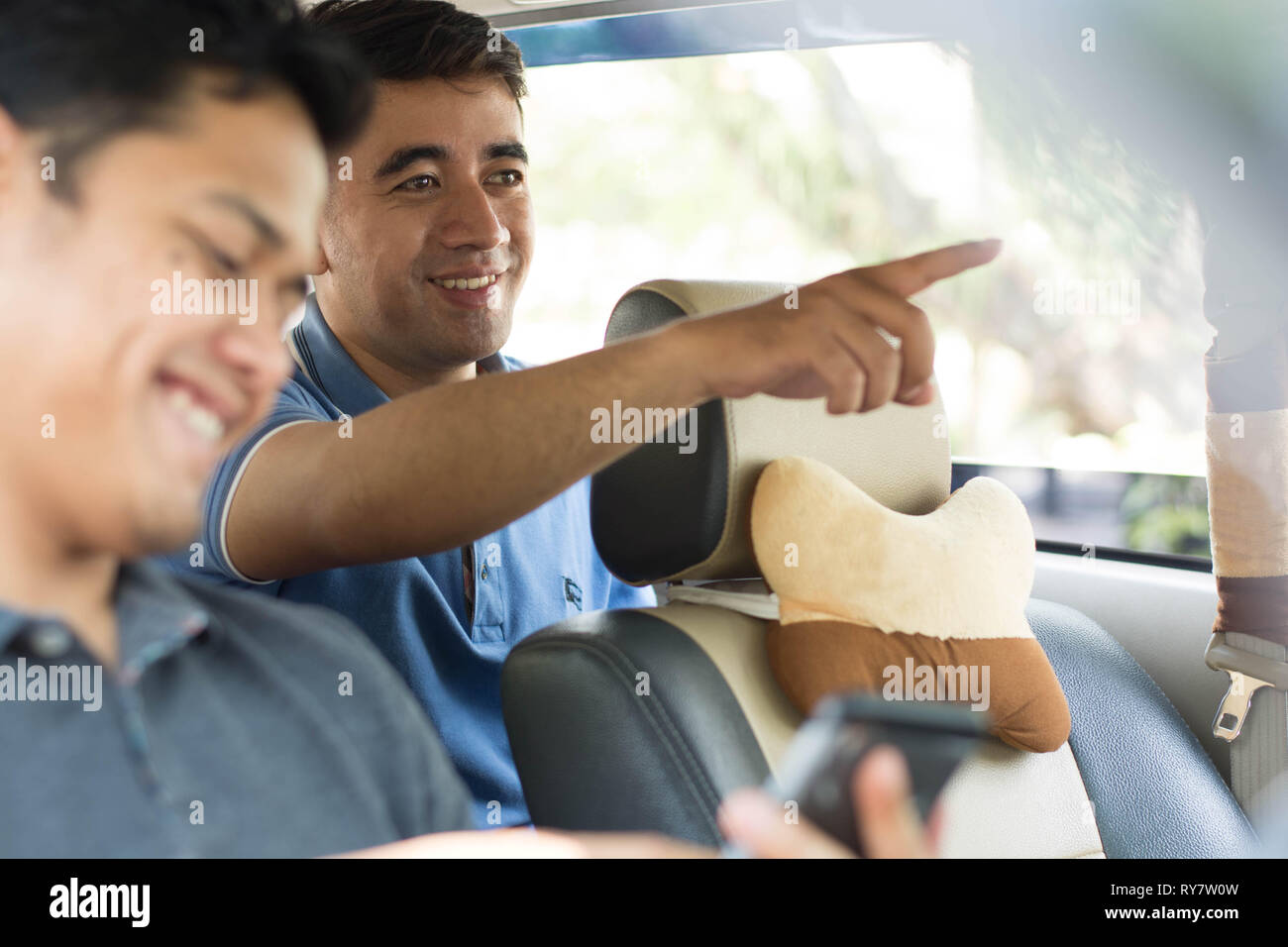 two handsome male friend or costumer pointing direction inside car ...