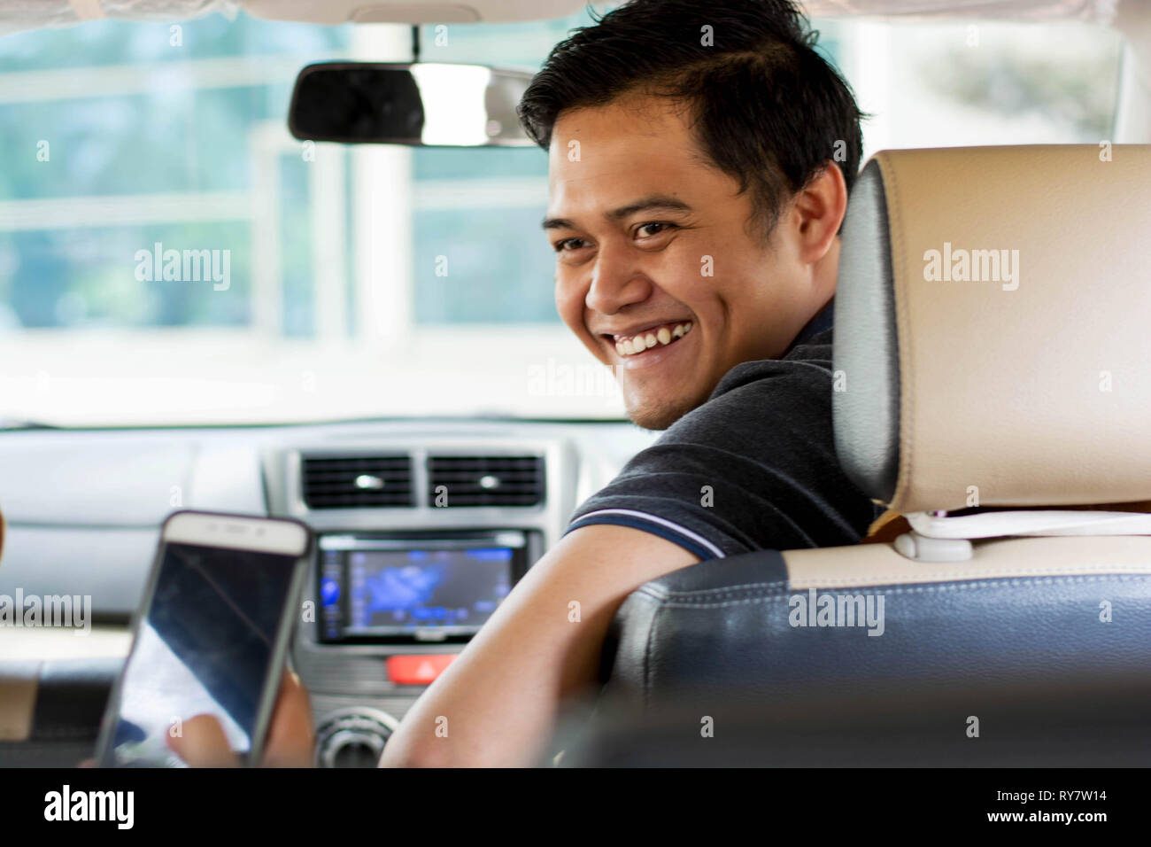 Online taxi driver smilling to costumer while the costumer showing ...