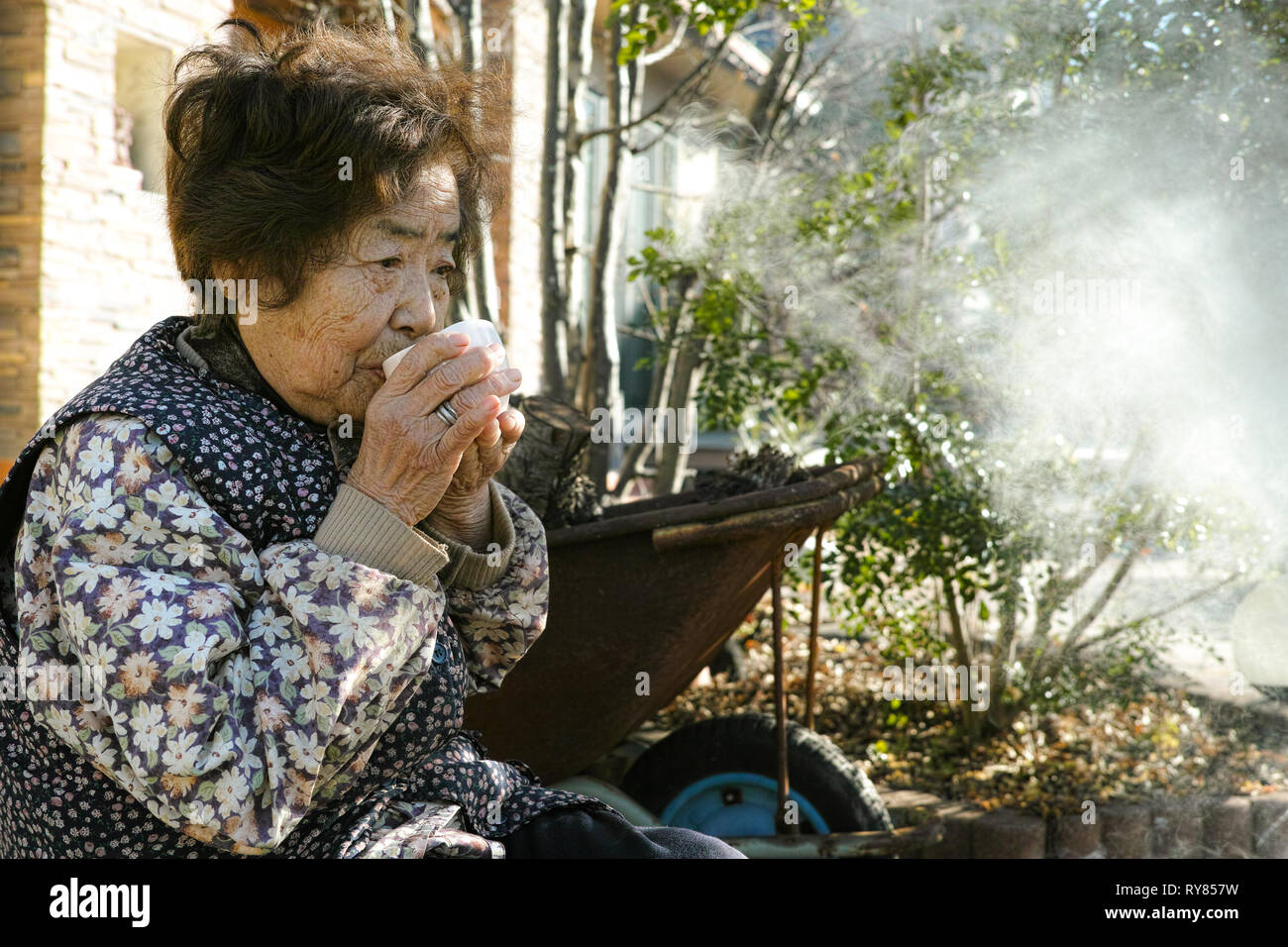 An old grandma drinking Japanese tea by herself outside Stock Photo - Alamy