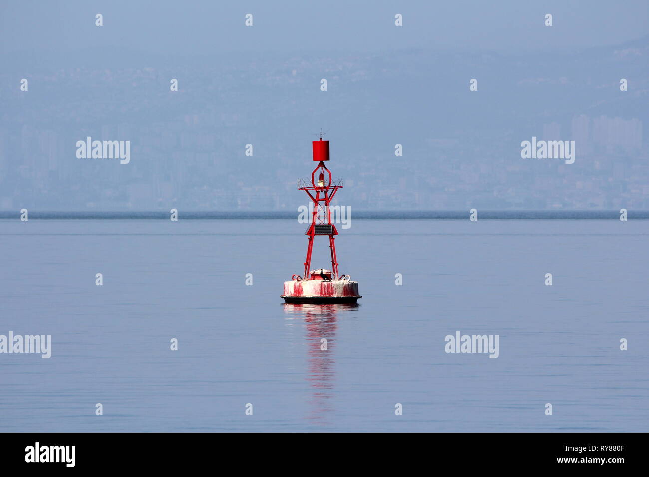 Small red navigational buoy with light on top and solar panels for ...