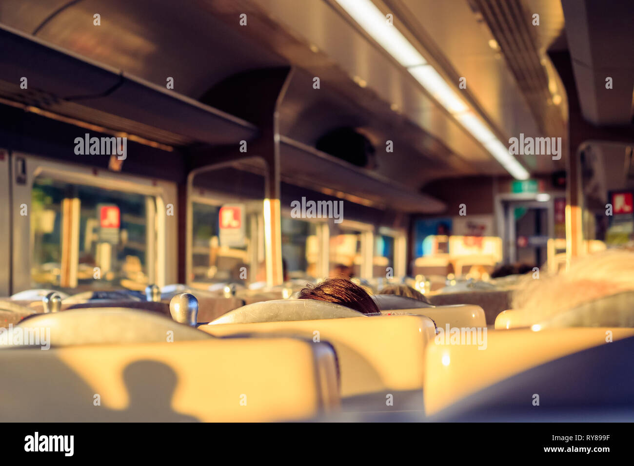 Back view of a passenger sitting in a moving train filled with golden ...