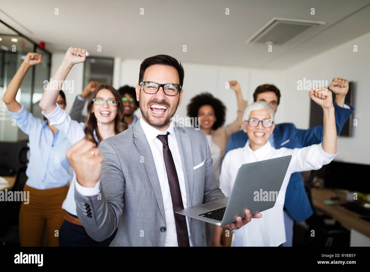 Happy business people celebrating success at company Stock Photo - Alamy