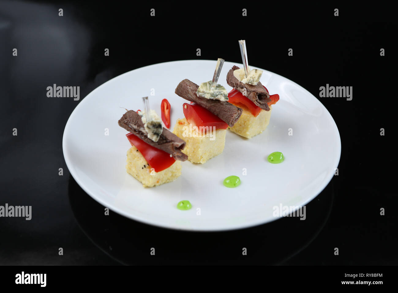 sliced meat, rolled into a roll, canapes with blue cheese and red ...