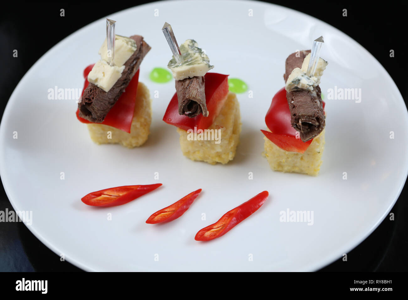 sliced meat, rolled into a roll, canapes with blue cheese and red ...