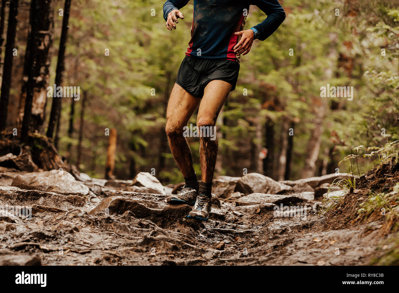 male runner running on dirty stones of forest trail marathon Stock ...