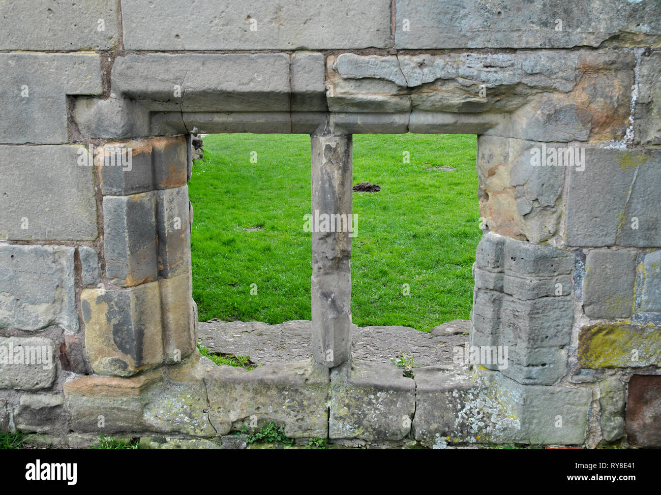 An old window in a stone wall showing a view of a grass lawn Stock ...