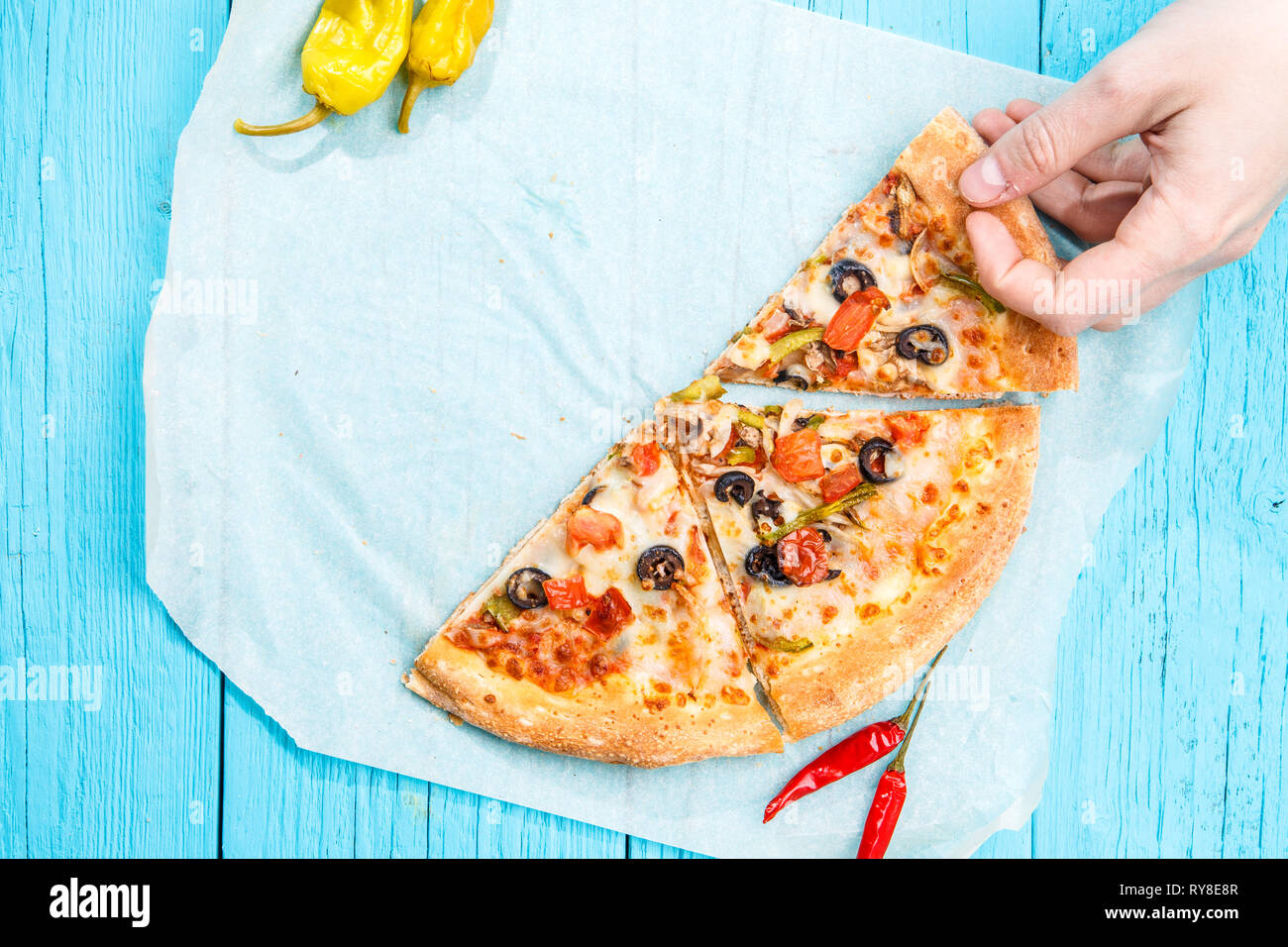 Image of pizza on table. Man take slice Stock Photo - Alamy