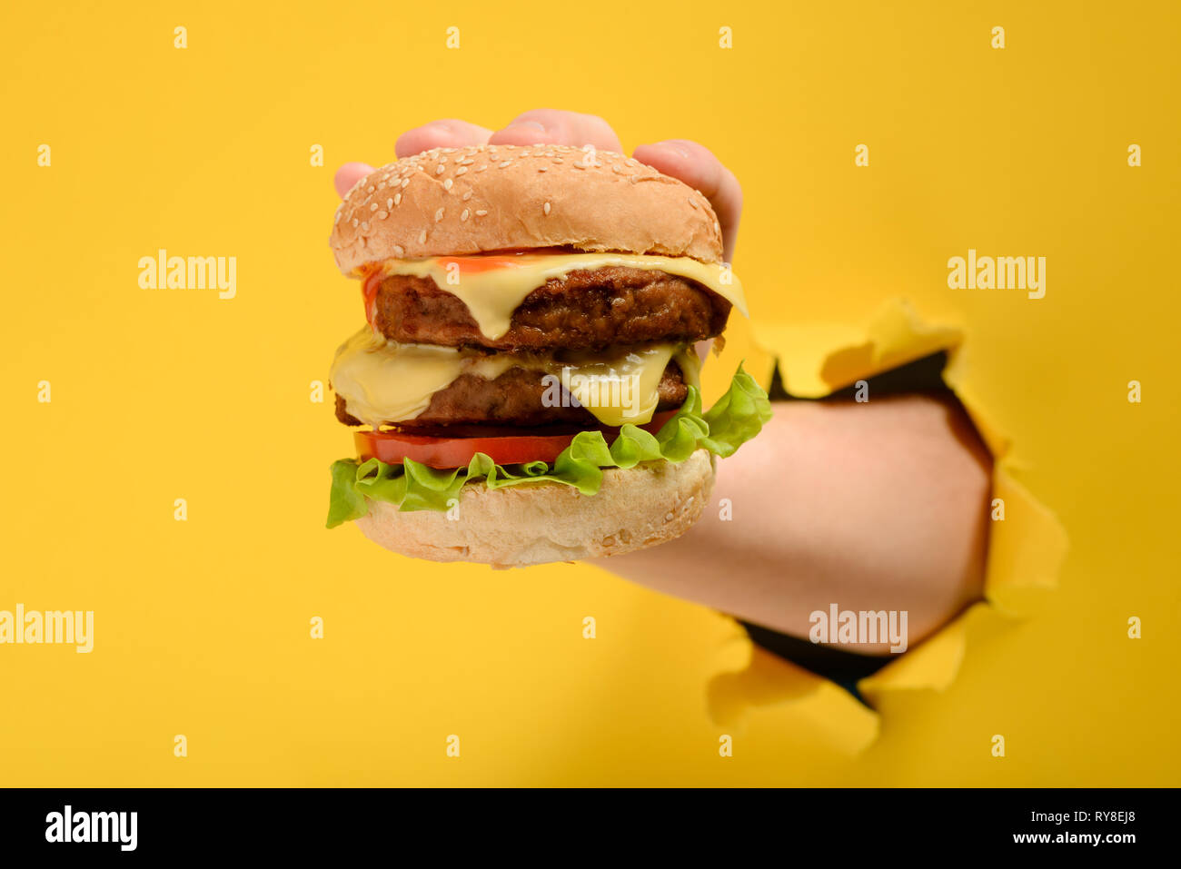 Hand holding an enormous burger Stock Photo - Alamy