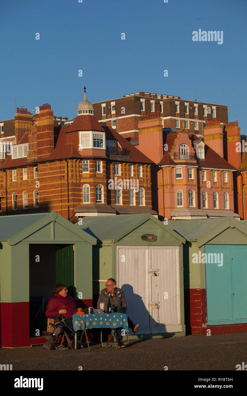 Couple picnicing on table outside their beach hut in February sunshine ...