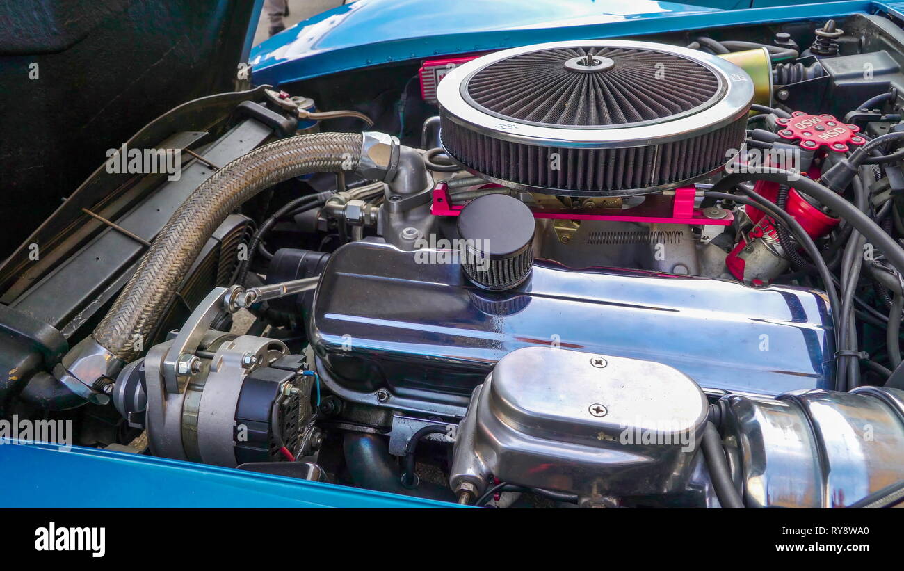 The engine of a blue car parked on the outside seen the valves ...