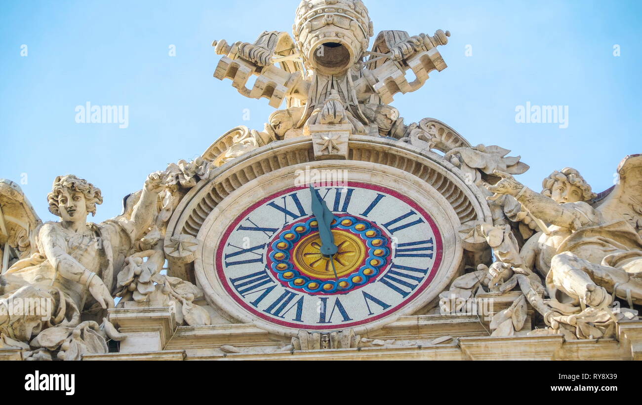 The clock about to strike 12 noon from the Basilica of Saint Peter in Vatican Rome Italy with an ...