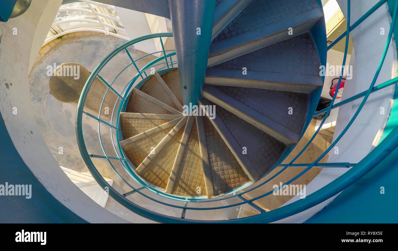 A twisted stairways going up the house with the blue colored side ...
