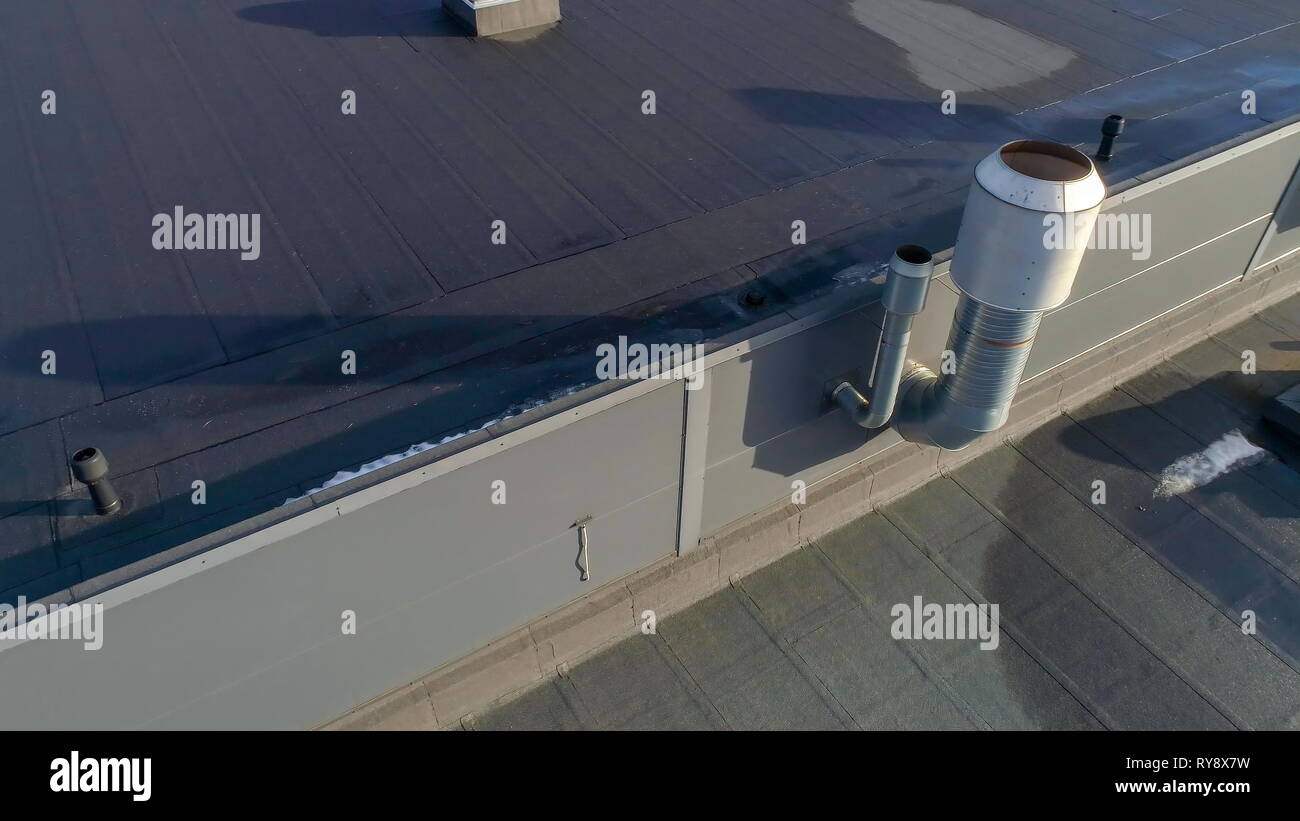 A big and small exhaust pipe on the tin roof a huge building in the ...