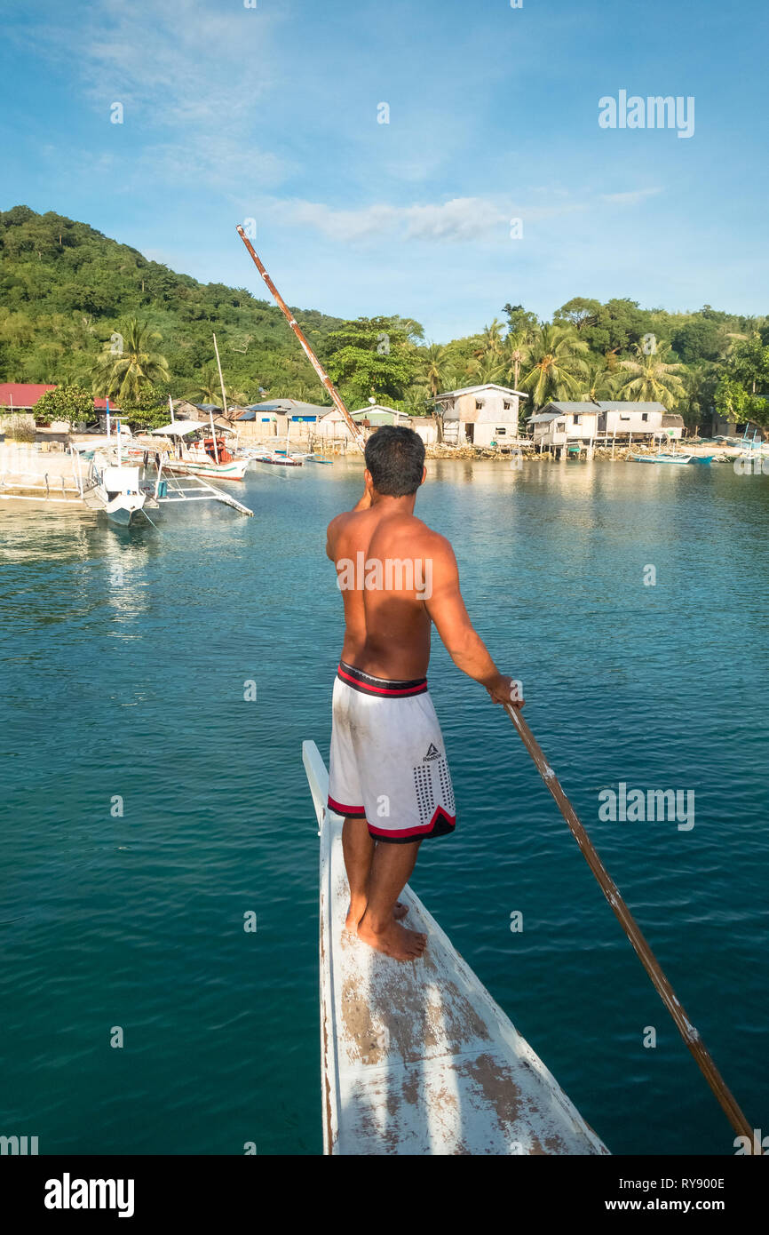 Filipino boat man guiding tour boat to port with bamboo pole ...