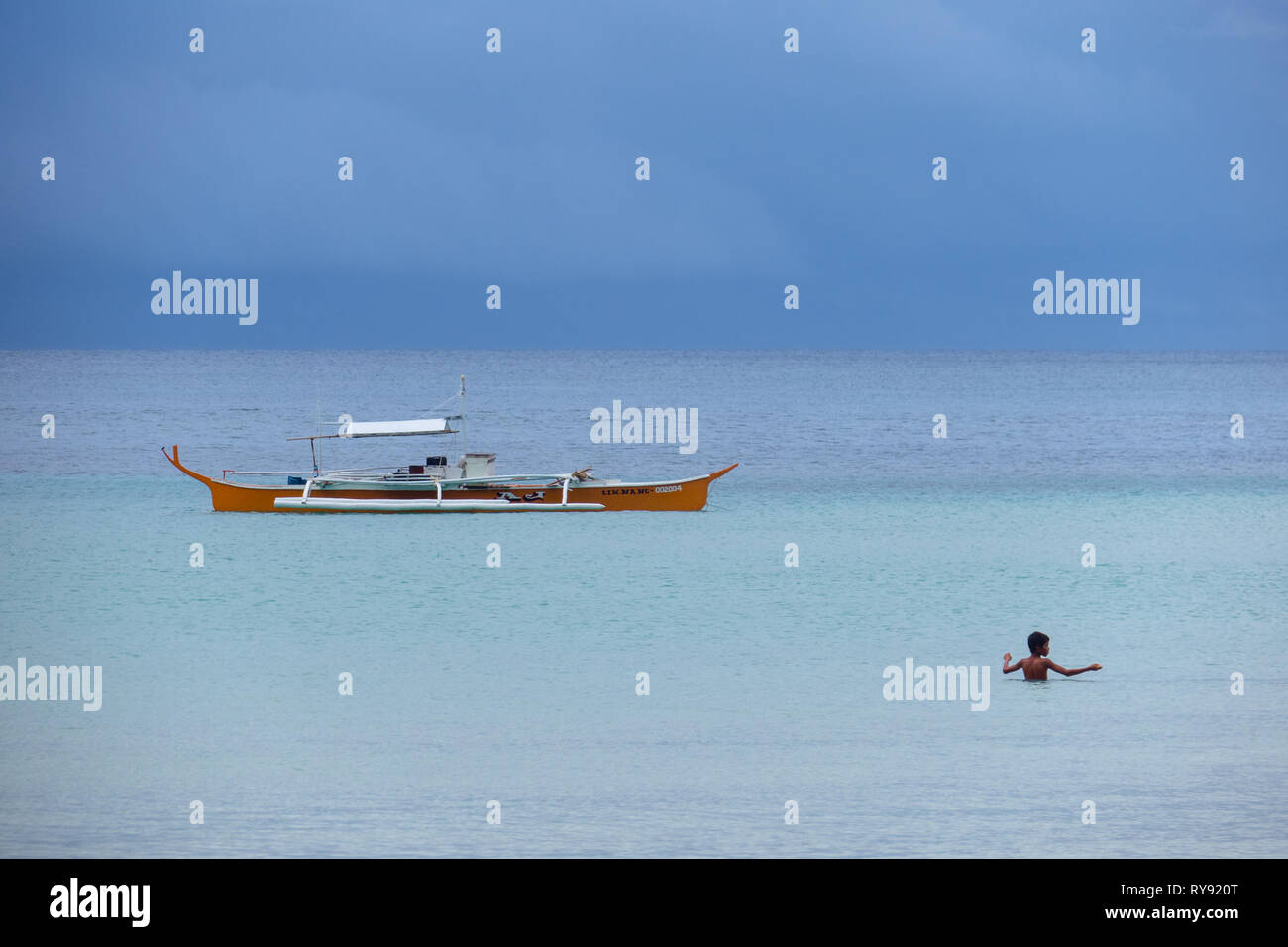Filipino Boy swimming in tropical sea near tour boat - Diapila Beach ...