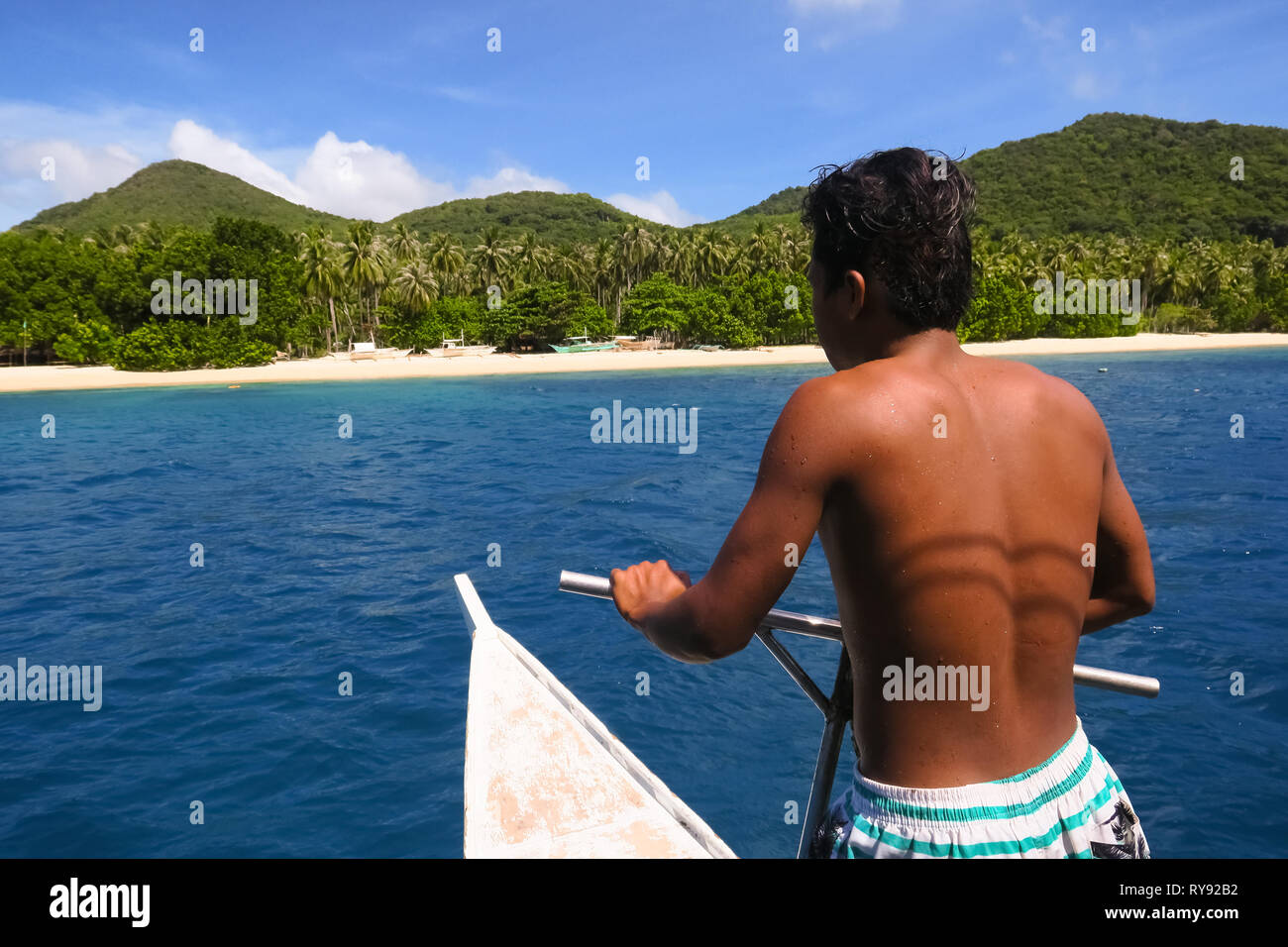 Tour boat man ready to throw anchor by tropical coastal landscape ...