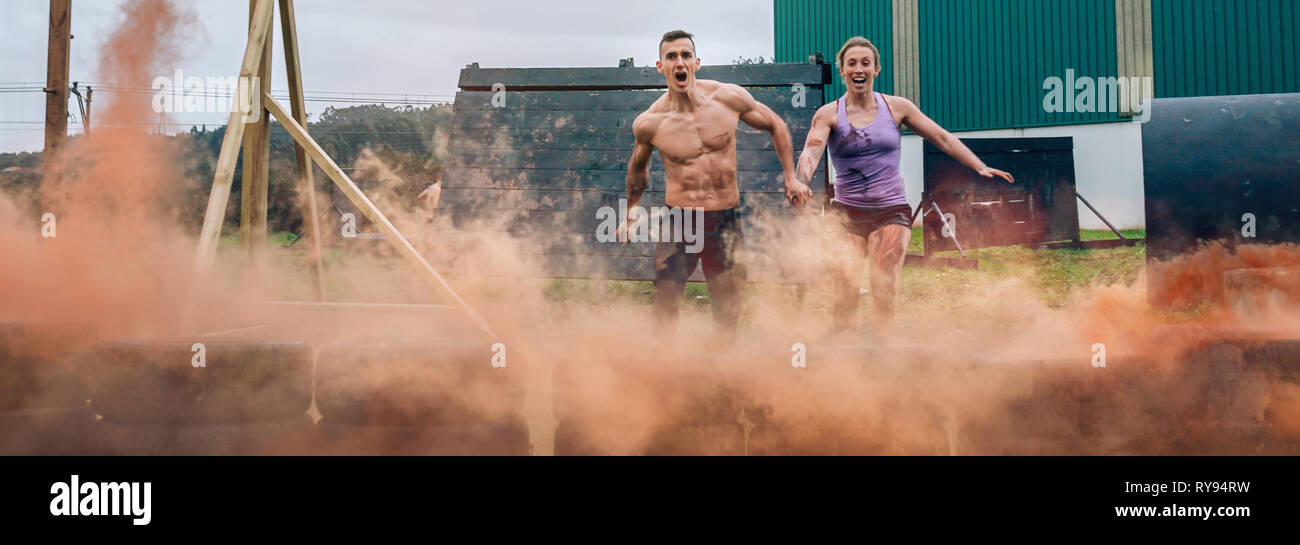 Athletes jumping finish line of an obstacle course Stock Photo - Alamy