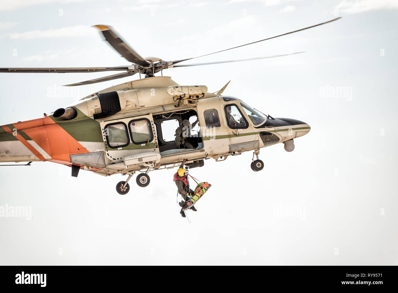 Rescue helicopter in flight winching rescuer Stock Photo - Alamy
