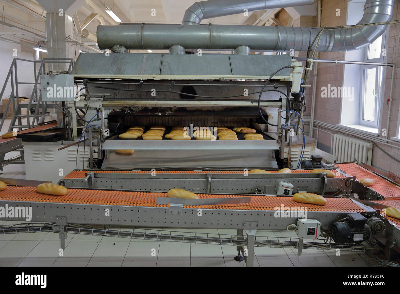 Baked breads processing on conveyor belt in factory Stock Photo - Alamy