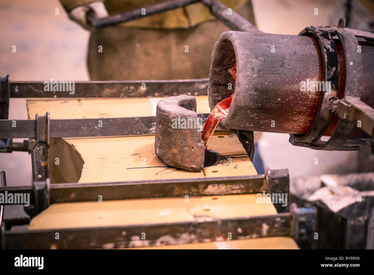 Crop male in uniform pouring molten metal from crucible in form on ...