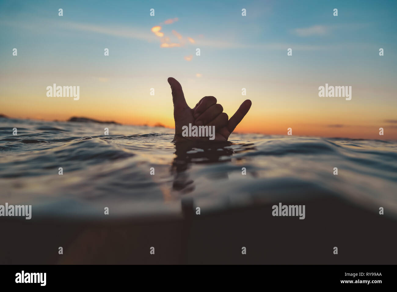 Closeup hand of human showing shaka sign above water surface with ...