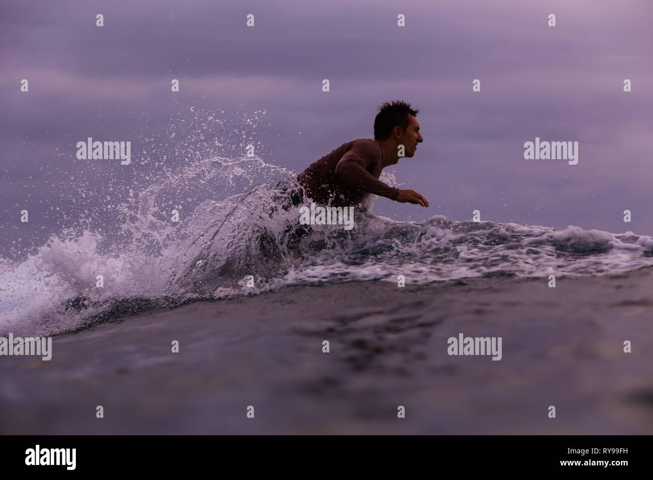 Side view of male floating on surf board between water of sea and ...